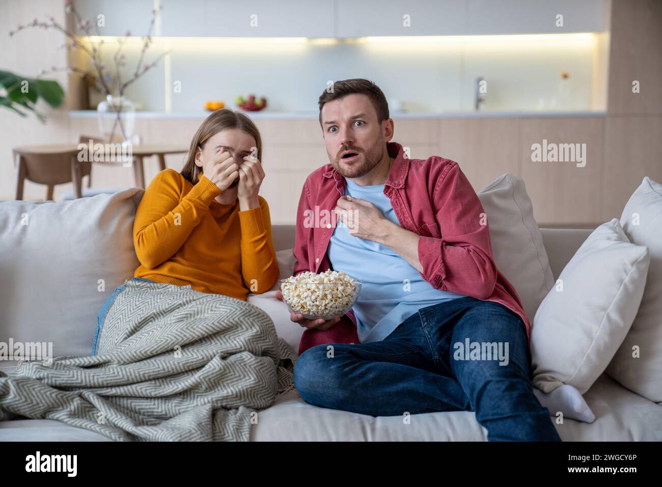 Scared afraid fearful family couple watching thriller horror eating ...