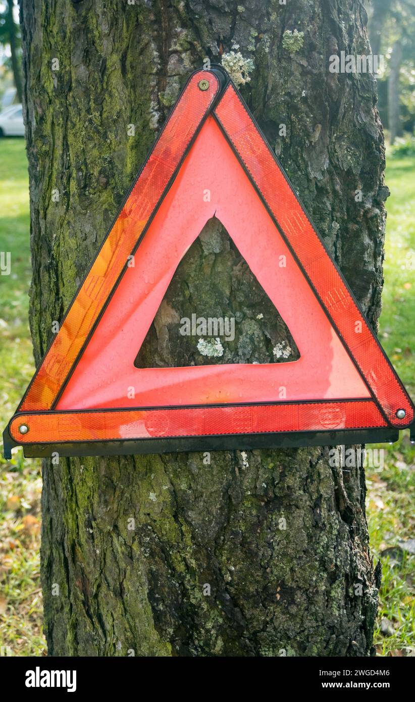 Red triangle, red emergency stop sign, red emergency symbol. On a tree ...