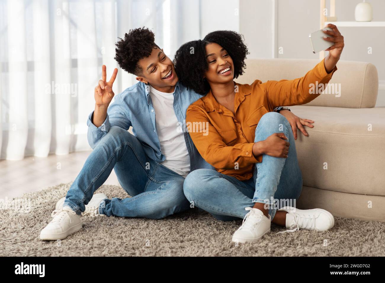 Sitting comfortably on the floor, a delighted young couple enjoys a ...
