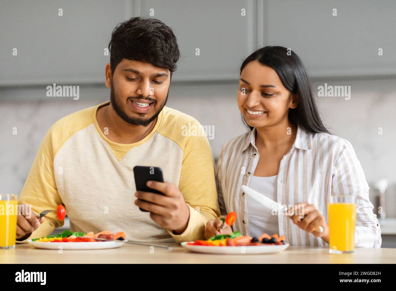 Millennial Indian Man And Woman Having Breakfast And Using Smartphone ...