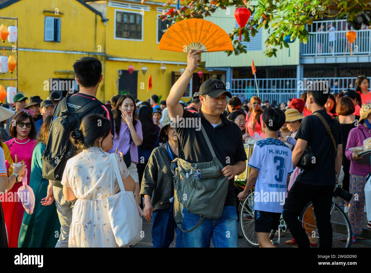 Tour guide with a fan leading tourists through the streets of Hoi An ...