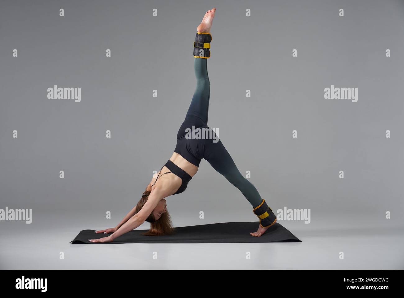 Mindful woman practicing yoga, while raising one leg in studio. Side ...