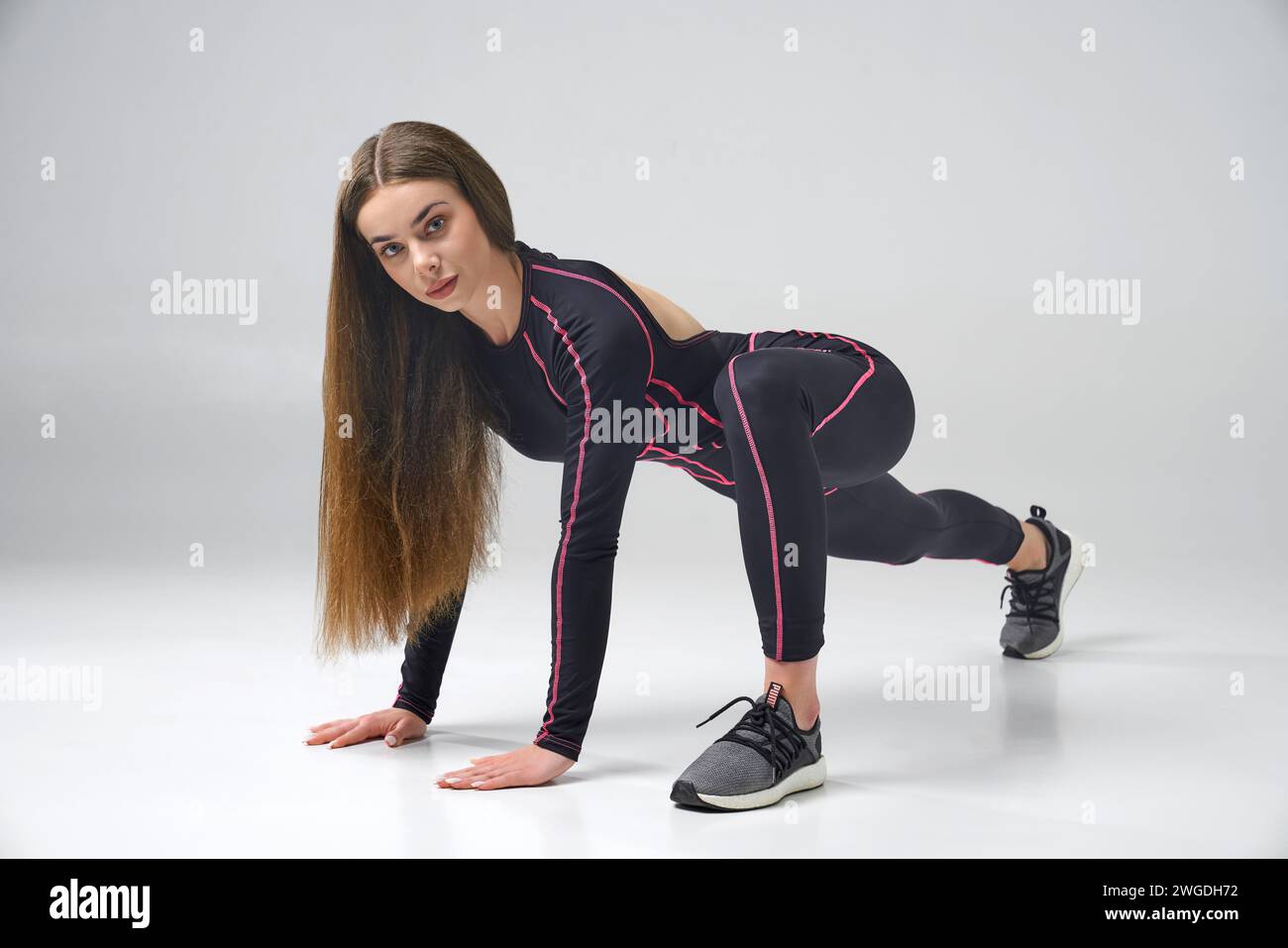 Sporty woman in black tracksuit stretching in studio. Side view of ...