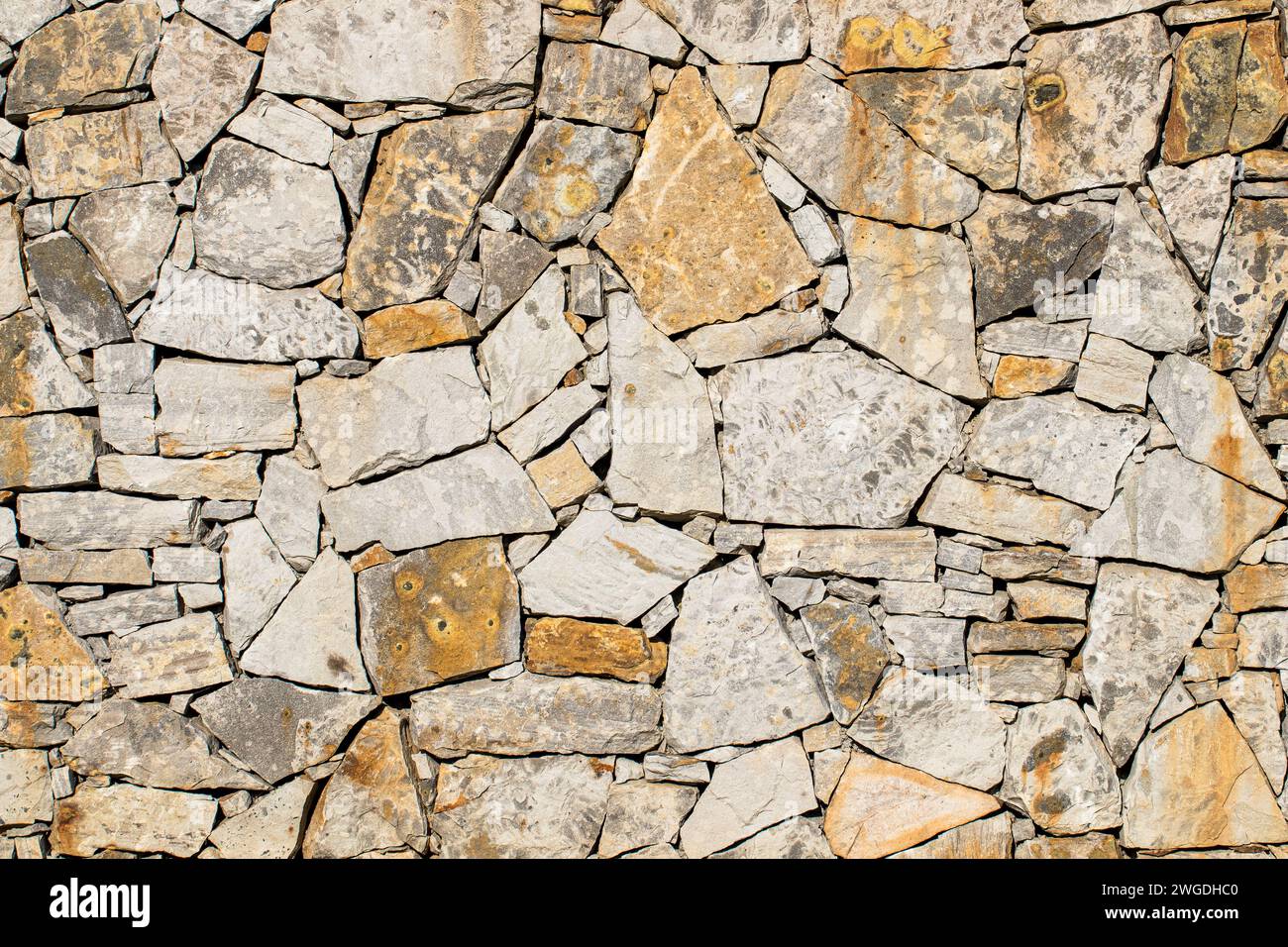 Yellow and grey rocks arranged in an outdoor wall-like structure Stock ...