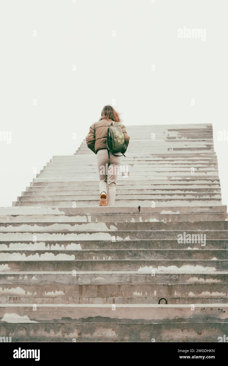 Woman walking on the stairs to nowhere. Girl climbing up stairs. Person ...