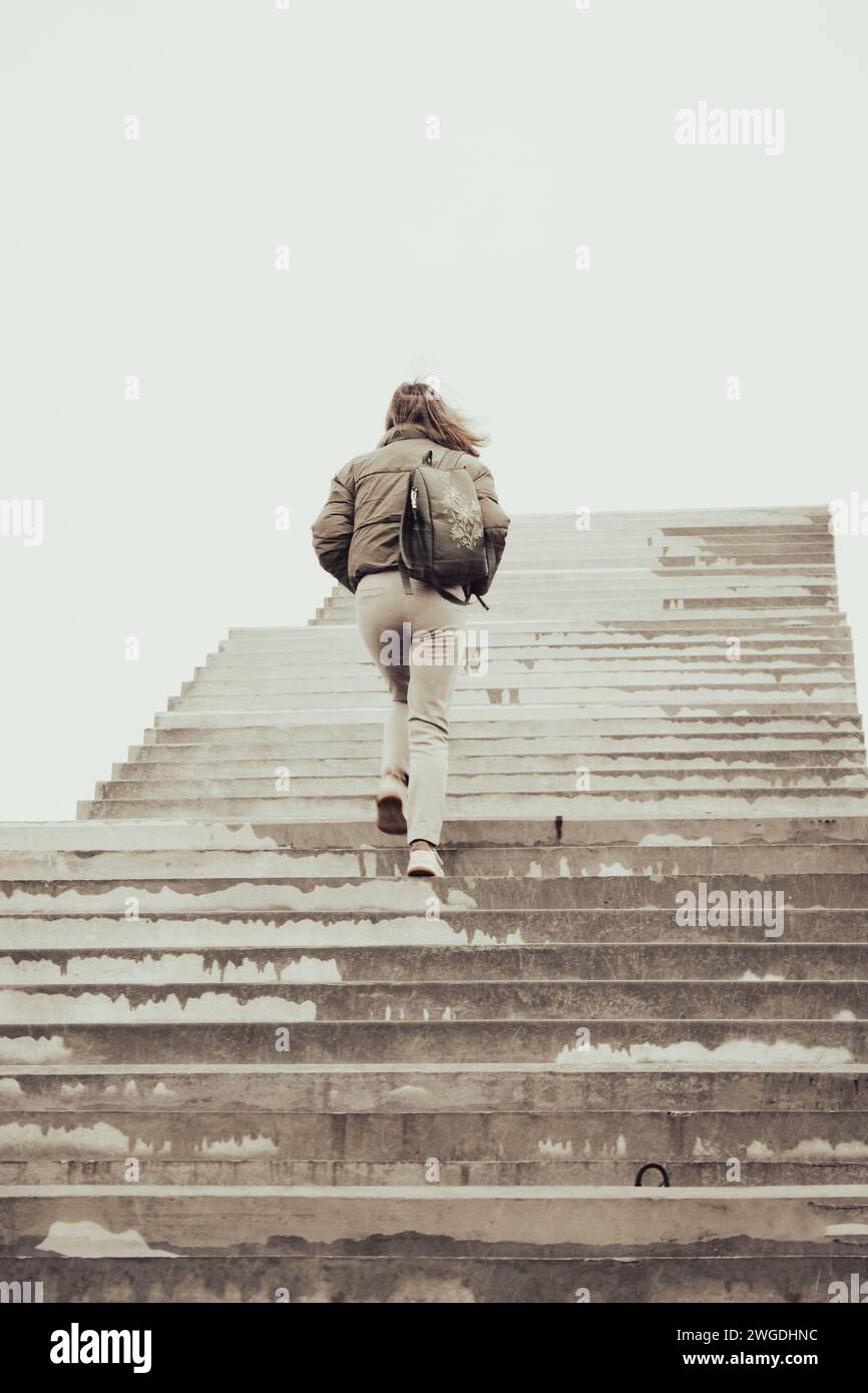 Woman walking on the stairs to nowhere. Girl climbing up stairs. Person ...