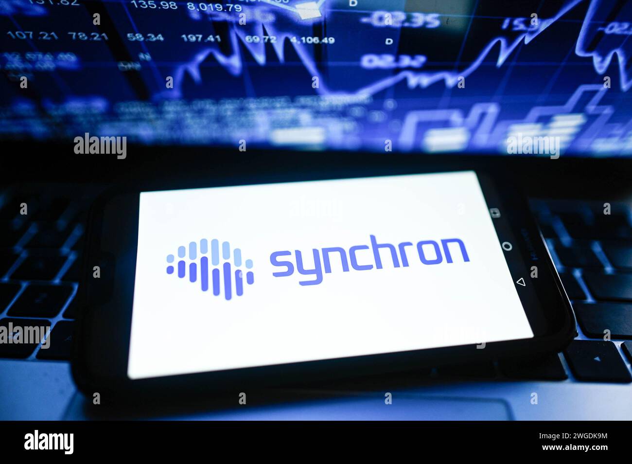 In this photo illustration a Synchron logo is displayed on a smartphone with stock market ...