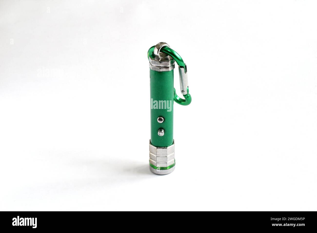 A laser pointer with a green metal body stands vertically on the table ...