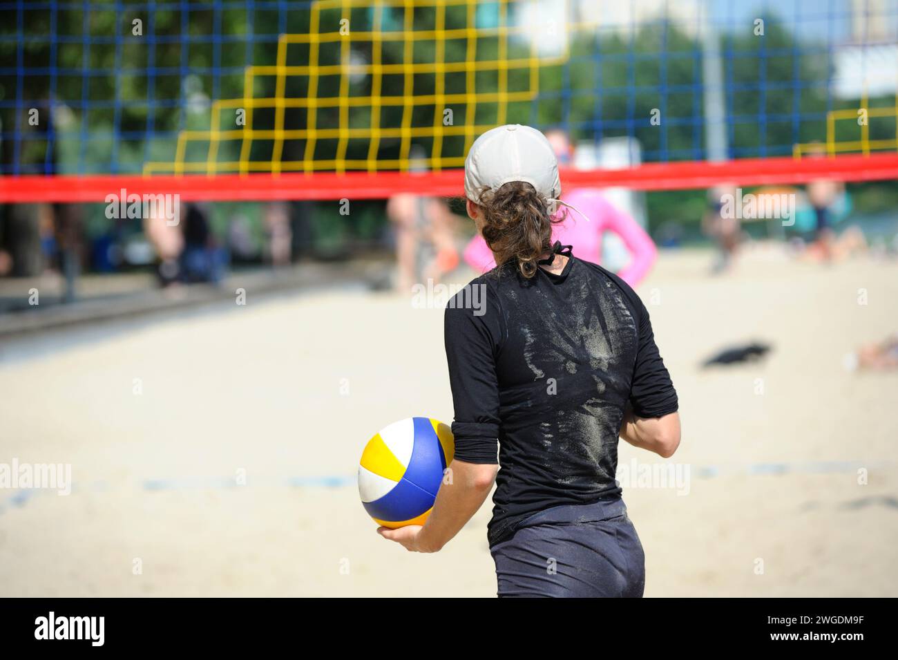 Beach volleyball. Young woman volley player standing in front of a net ...