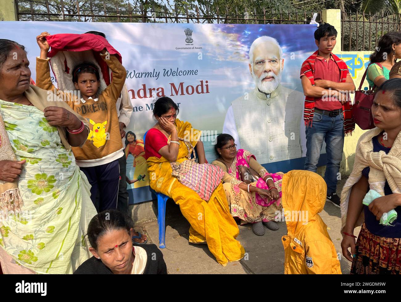 February 4, 2024: People sits next to a poster of Indias Prime Minister ...