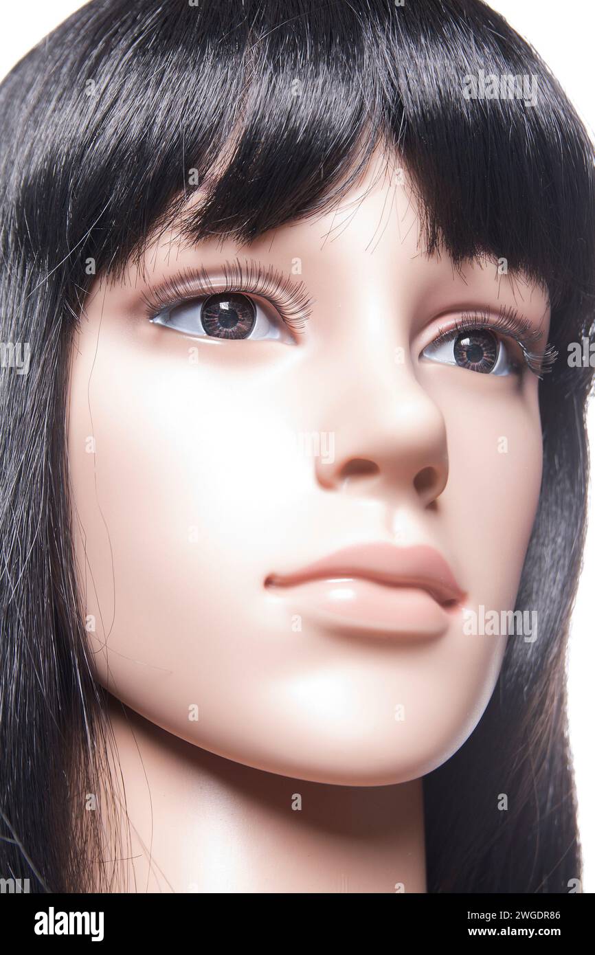 Plastic woman mannequin closeup with black long hair posing on a white ...