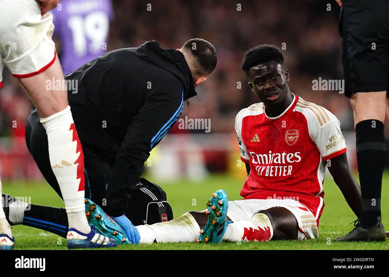 Arsenal's Bukayo Saka (right) receives treatment before being ...