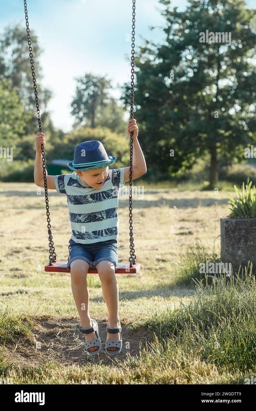 Little boy swinging on playground. Happy cute excited child on swing Stock Photo - Alamy