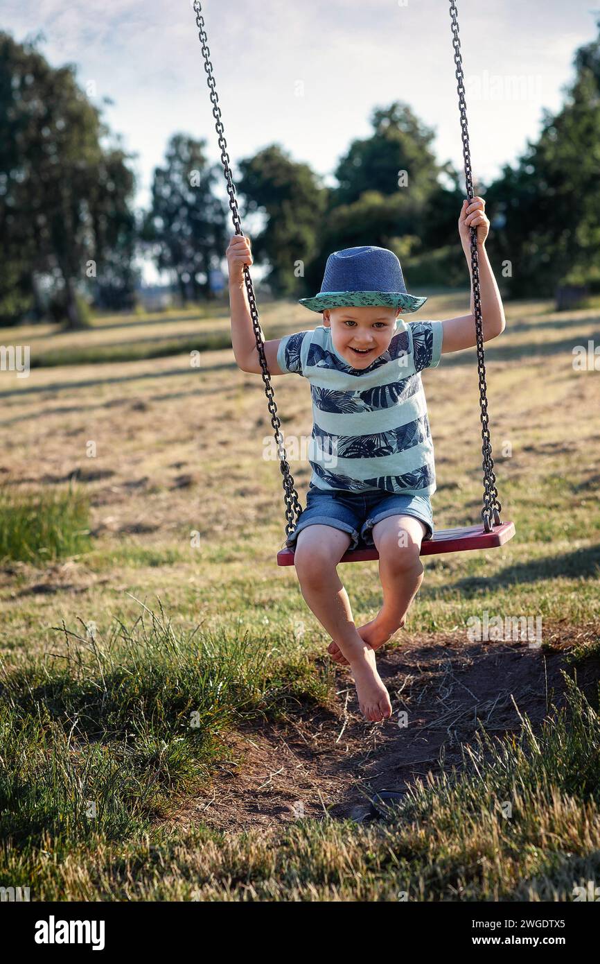 Little boy having fun on a swing on the playground in public park on ...