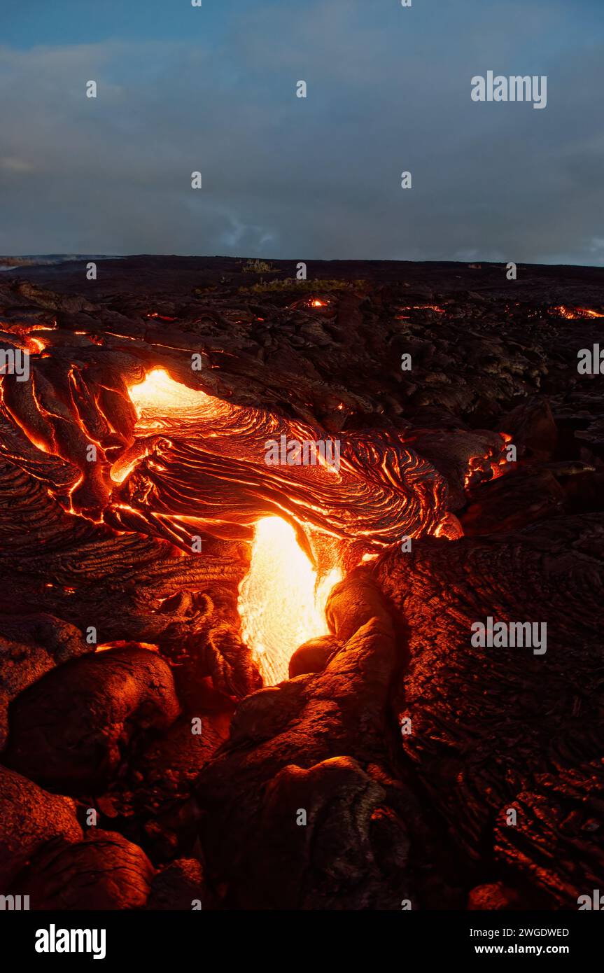 A lava flow emerges from an earth column and flows in a black volcanic ...