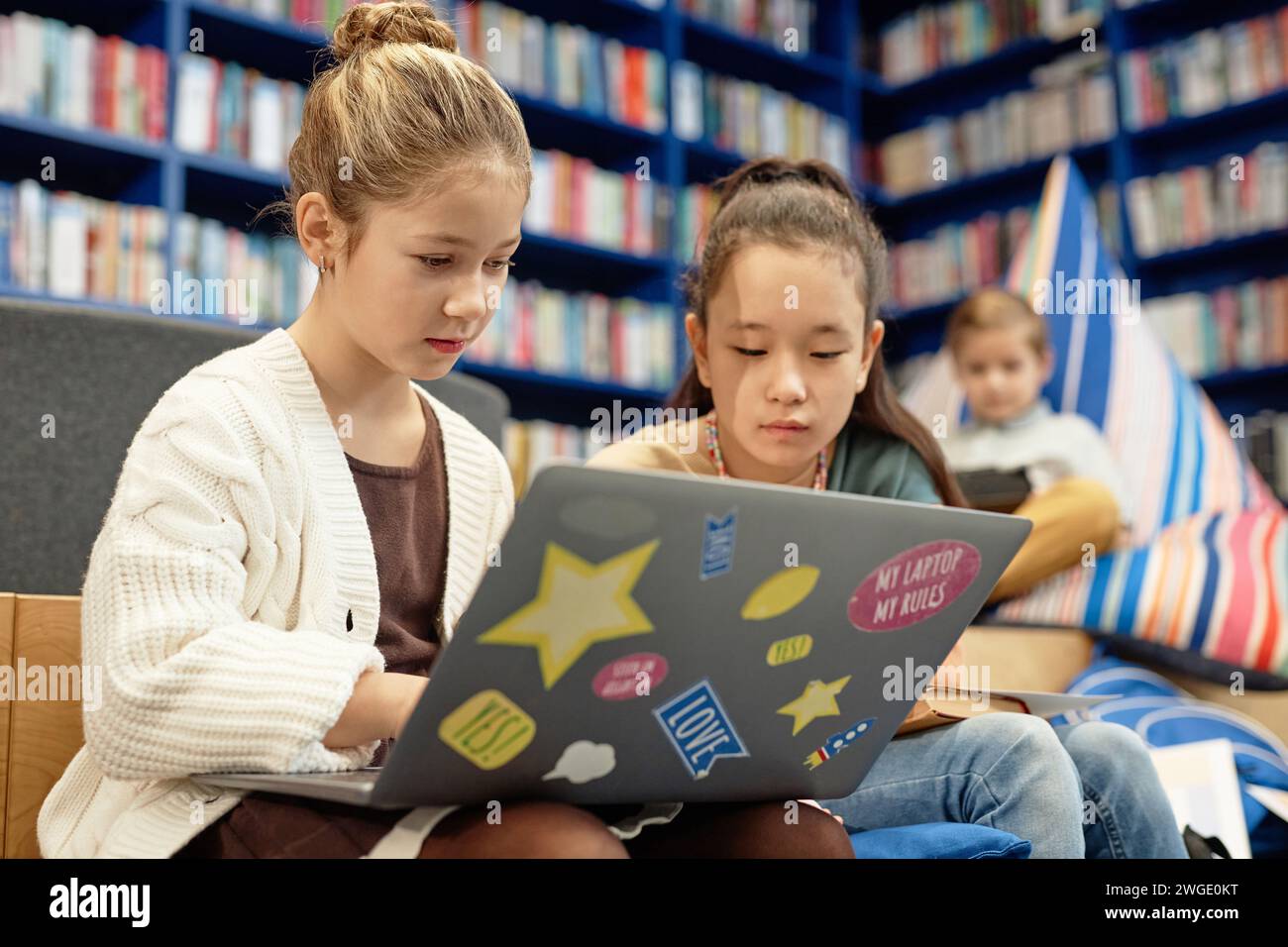 Portrait of two young girls using laptop computer in colorful school ...