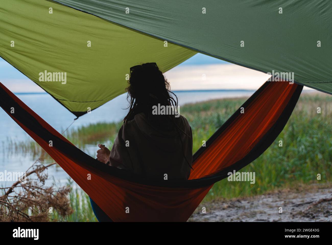 back view of hippie woman with dreadlock hairstyle lying in hammock at ...