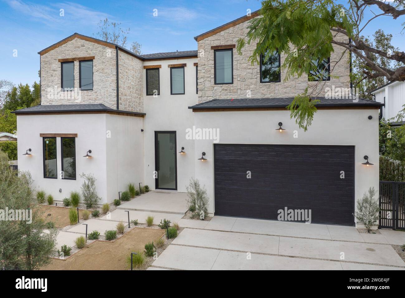 A front of house with driveway, garage, and paved pathway Stock Photo ...