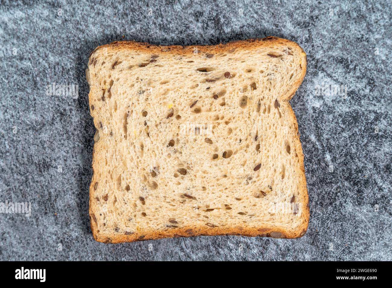 Slice of fresh toast bread with seeds on dark background. Top view ...