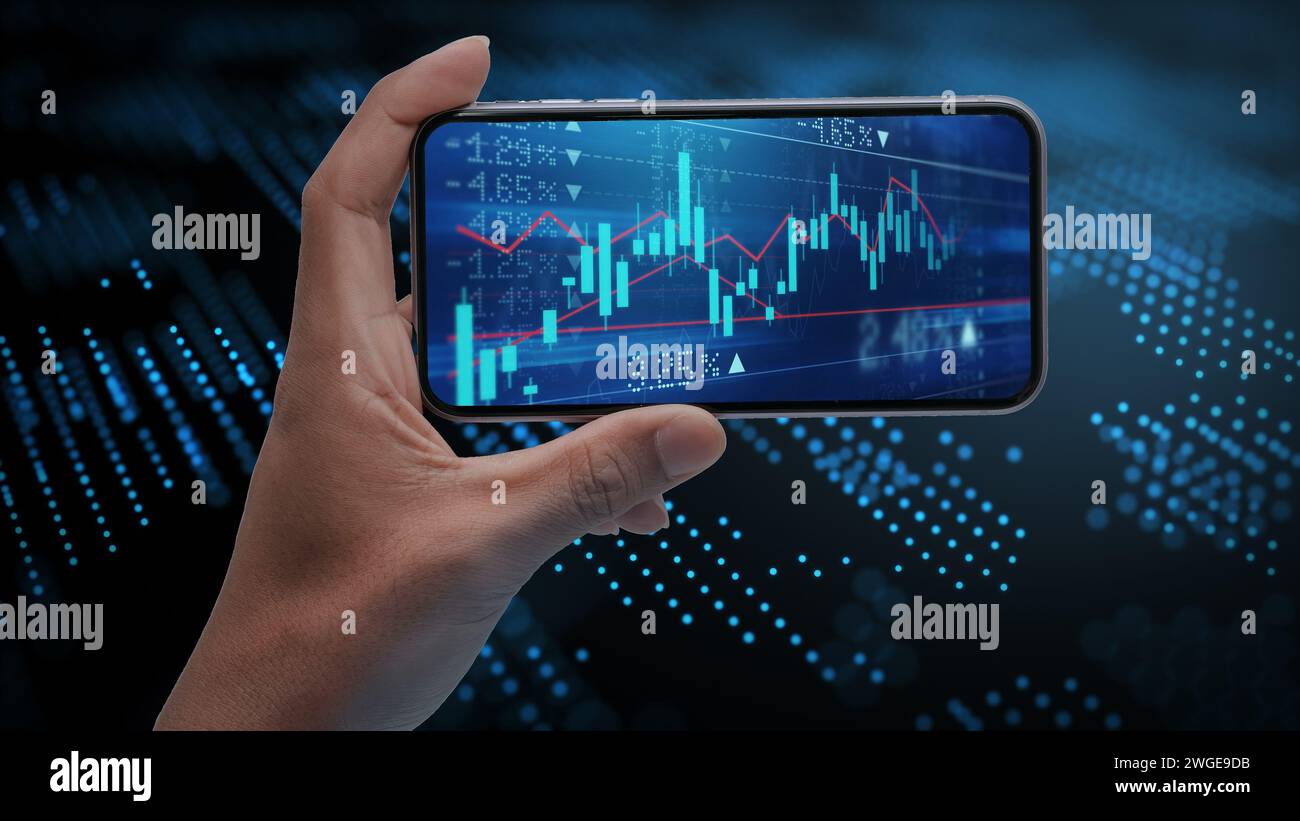 Mans hand holding cell phone with stock charts on screen with high tech ...
