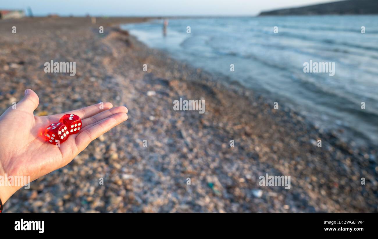 A woman's hand with red dice on a beach background Stock Photo - Alamy