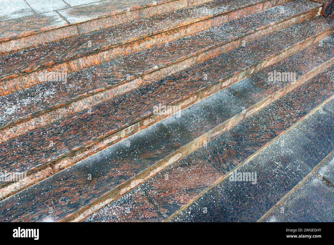 Deicing chemicals on stairs in winter. Salt grains on icy stone steps ...