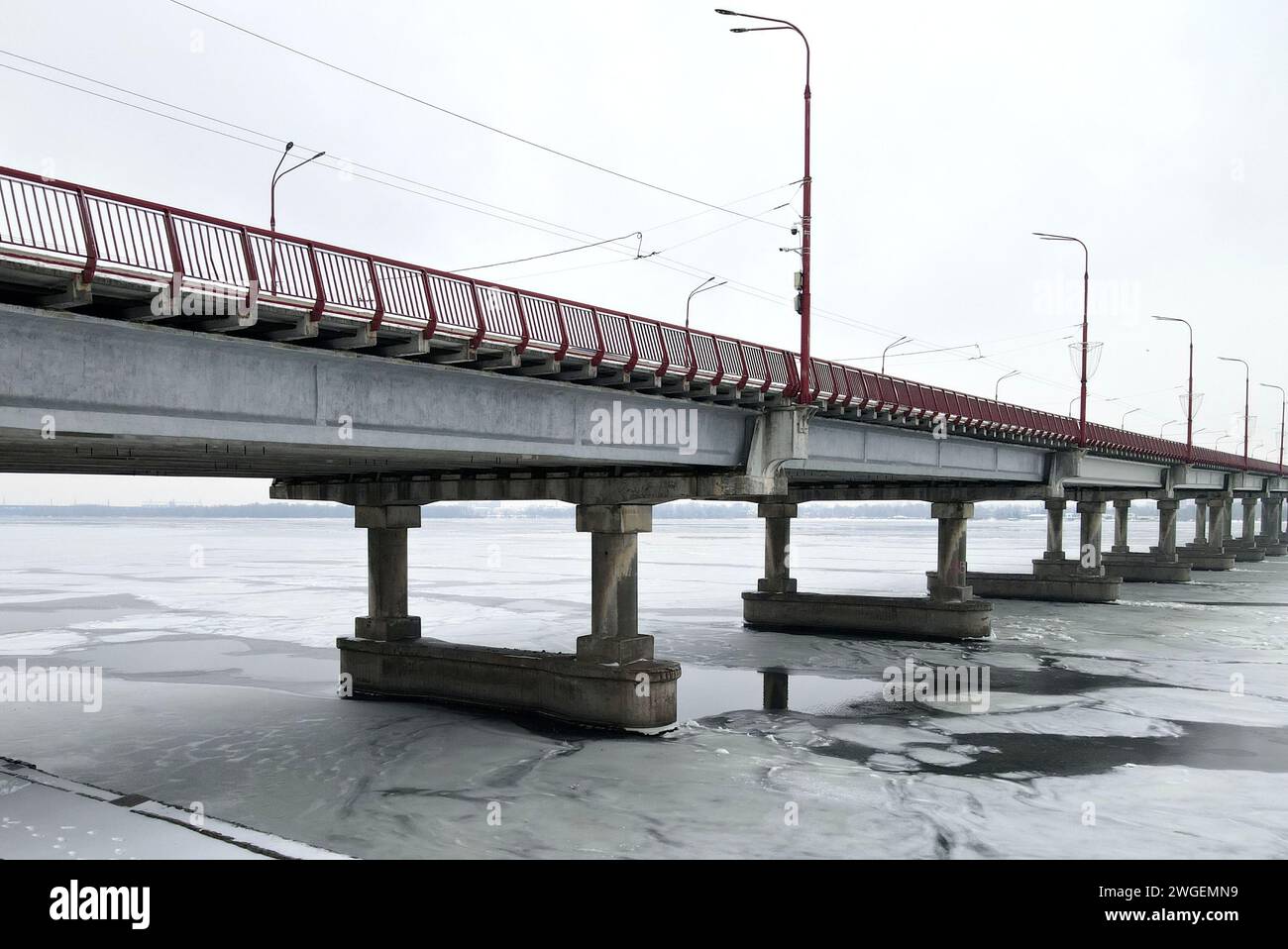 Road bridge on winter river. Large concrete bridge with red railings ...