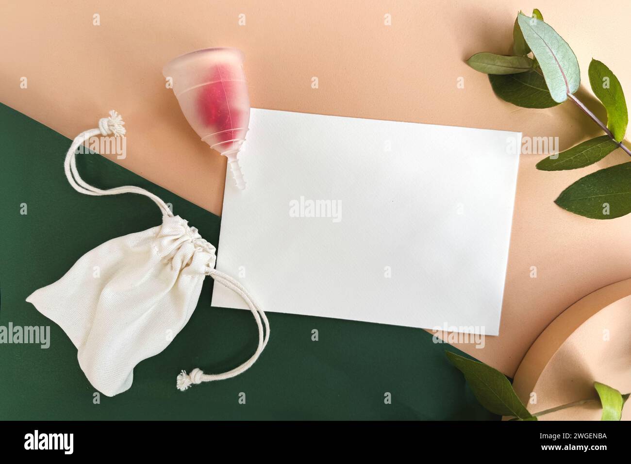 Menstrual cup and contraceptive pills on beige and green background ...