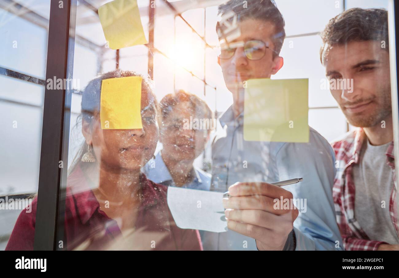 A group of business people behind a glass wall in the office sticking ...