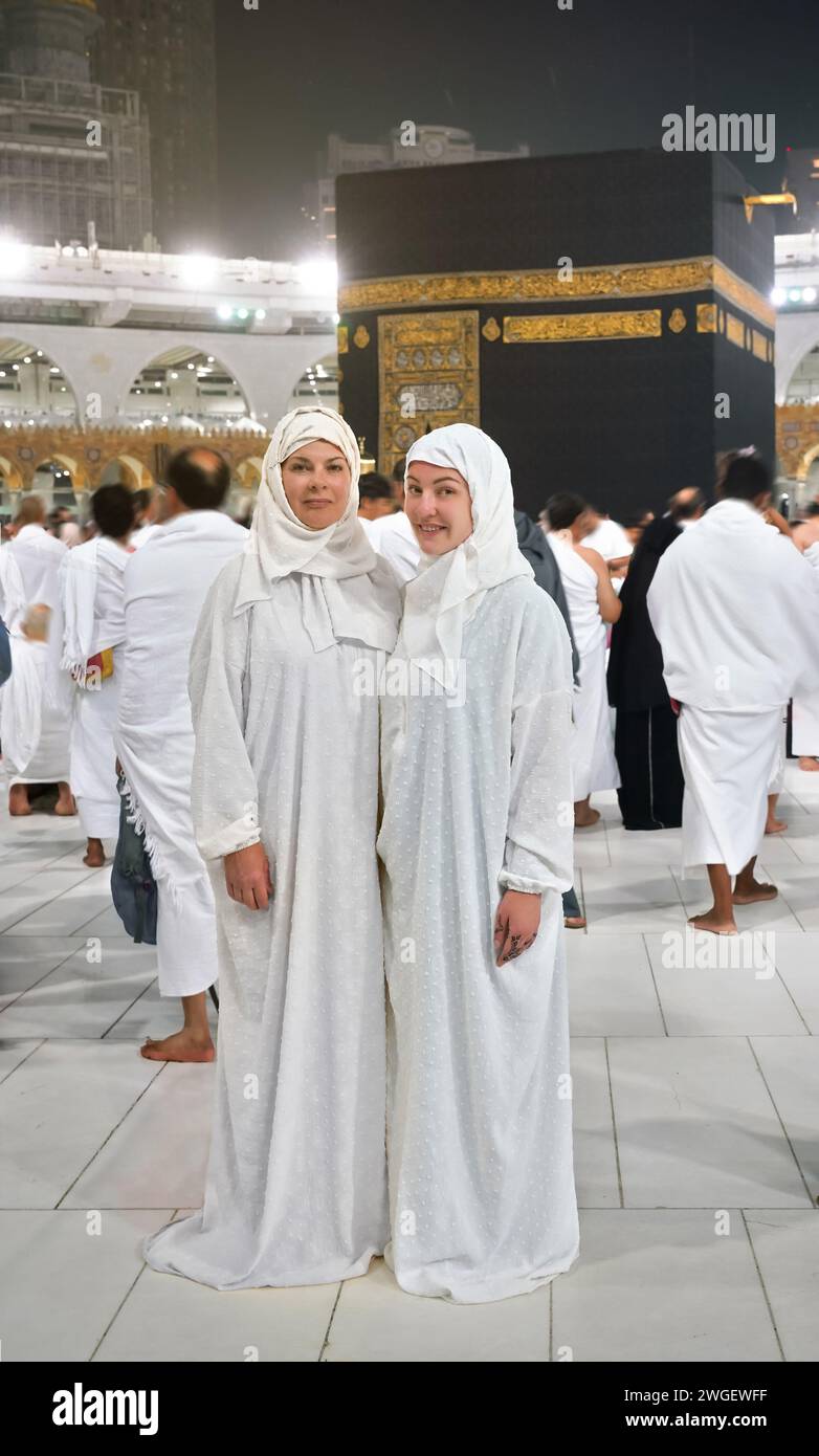Two caucasian women in long white dress standing in front of the Kaaba ...