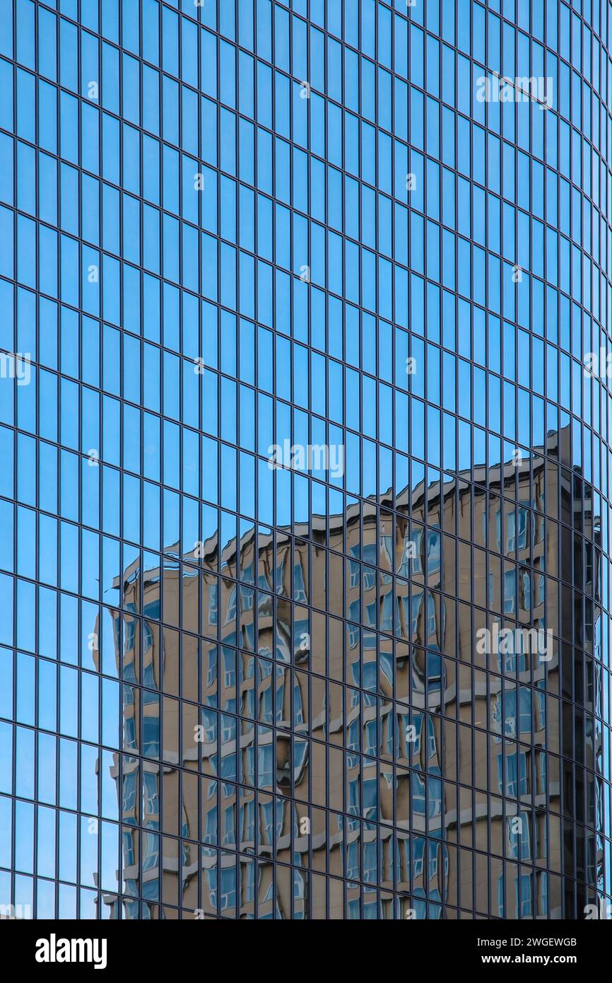 Blue glass skyscraper with the reflection of another building in the ...