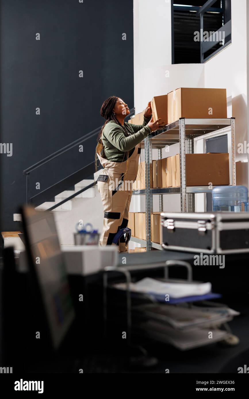 Warehouse employee taking out cardboard box from metallic shelf ...