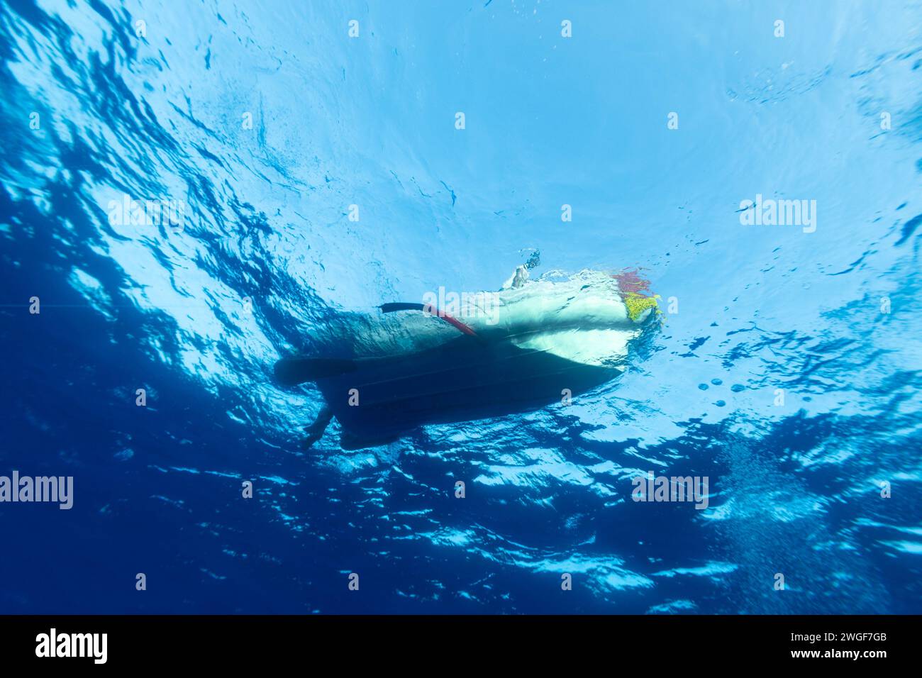 View from bellow of small dive boat floating above in clear blue ...