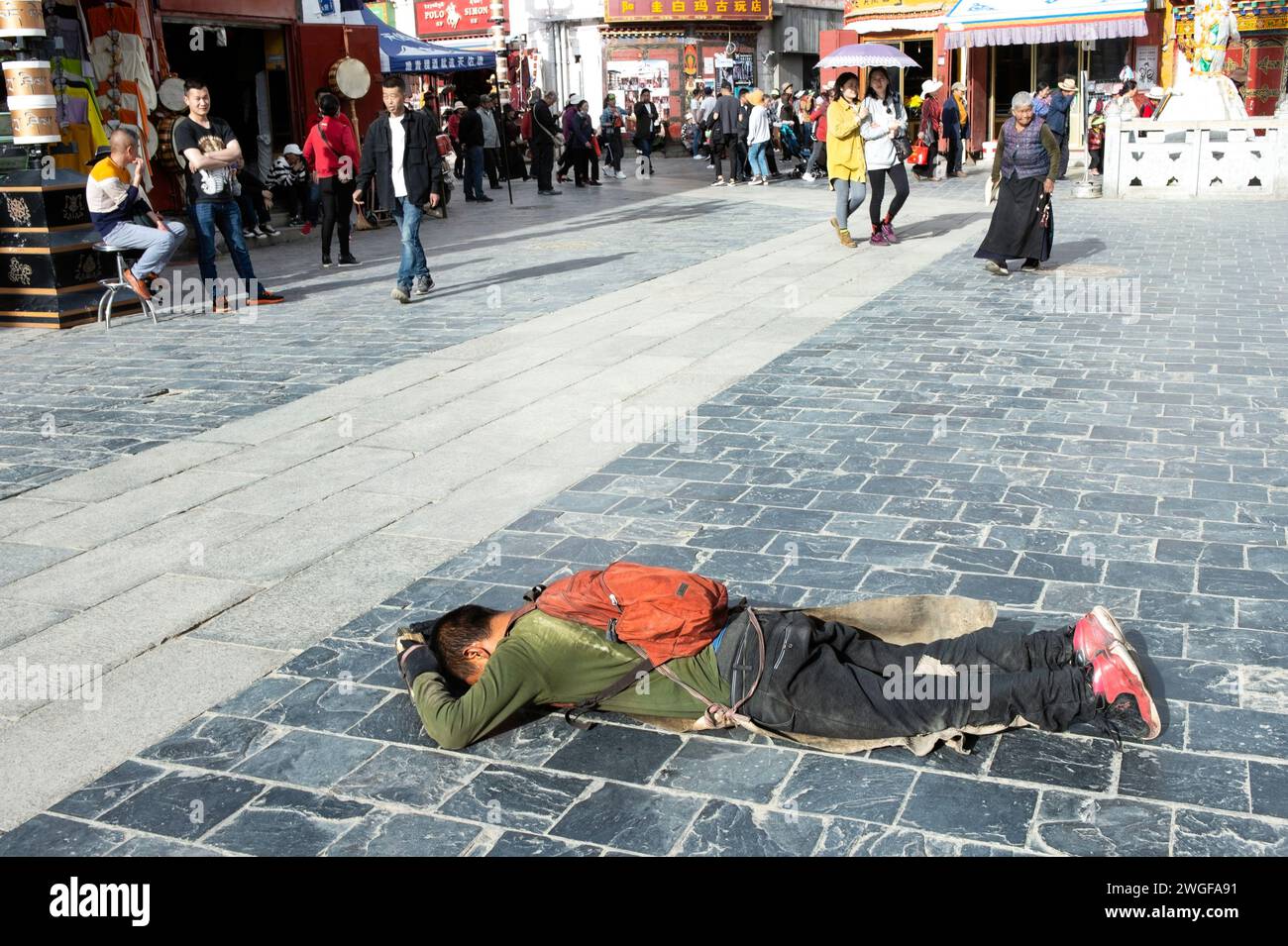A man lies down with his face touching the ground in prostration to the ...