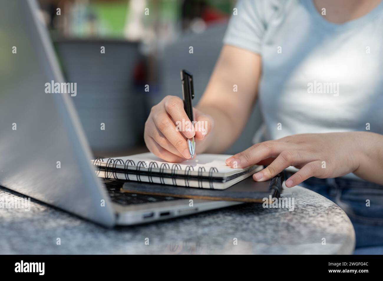 A close-up shot of a woman writing something in her notebook at an ...