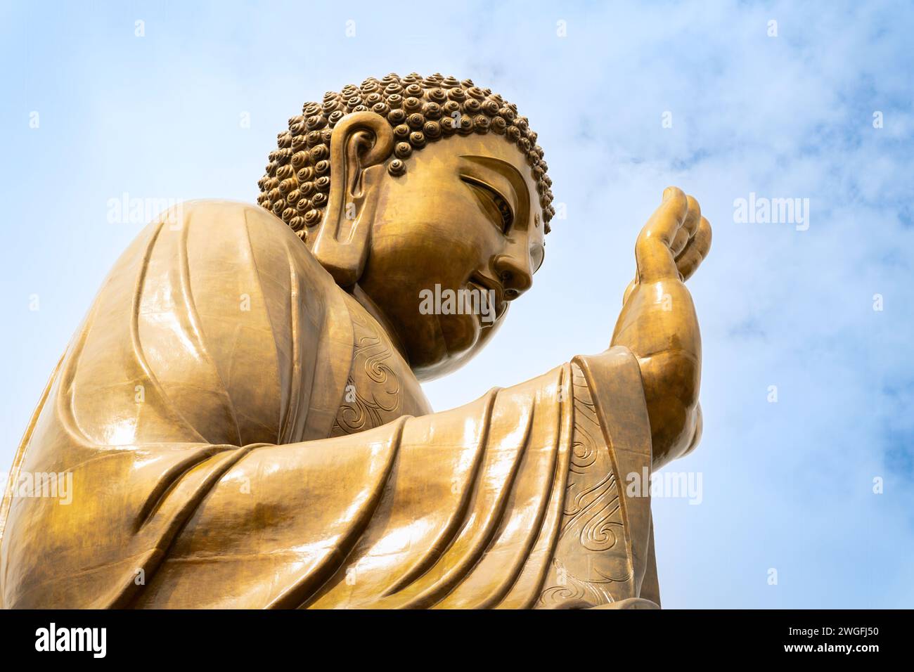 Tall statue of Buddha with raised hands reaching skyward Stock Photo ...
