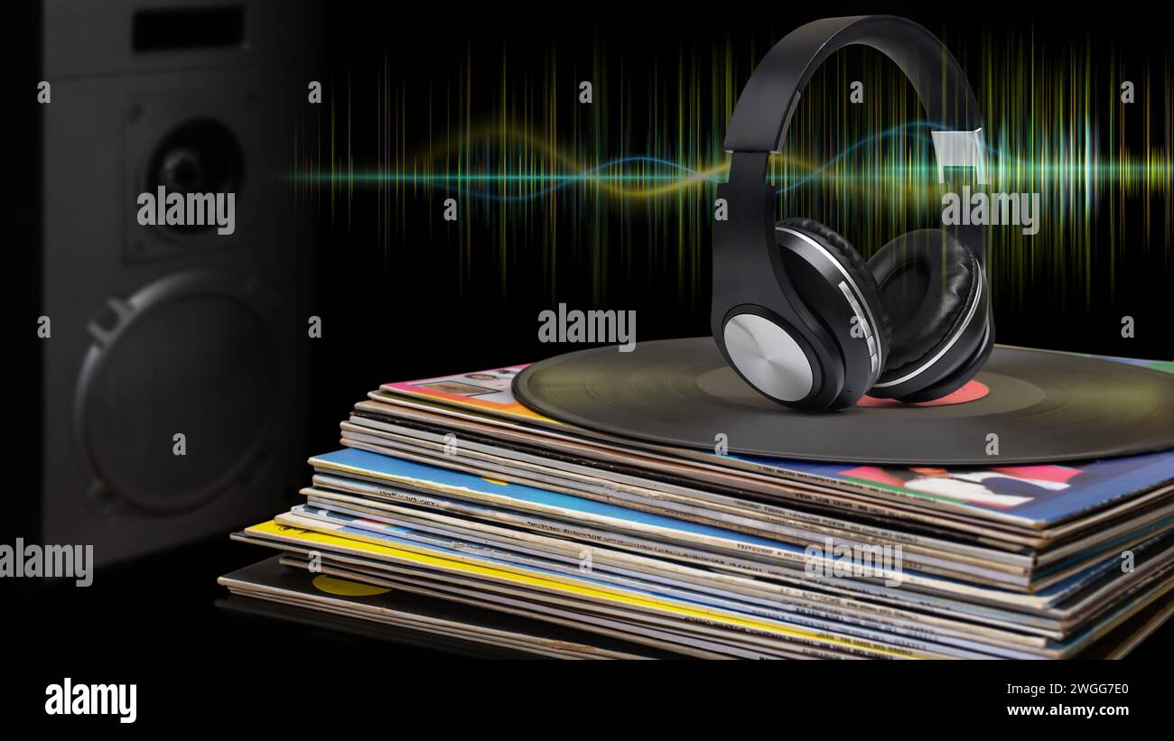 Pile of old vinyl discs, headphones and loudspeaker on black background ...