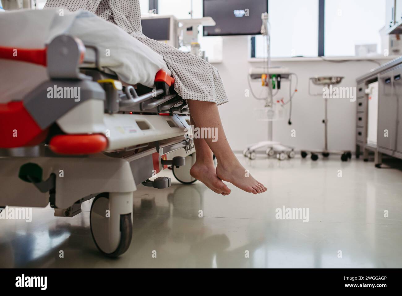Close up of barefoot legs of patient, sitting on hospital bed in ...