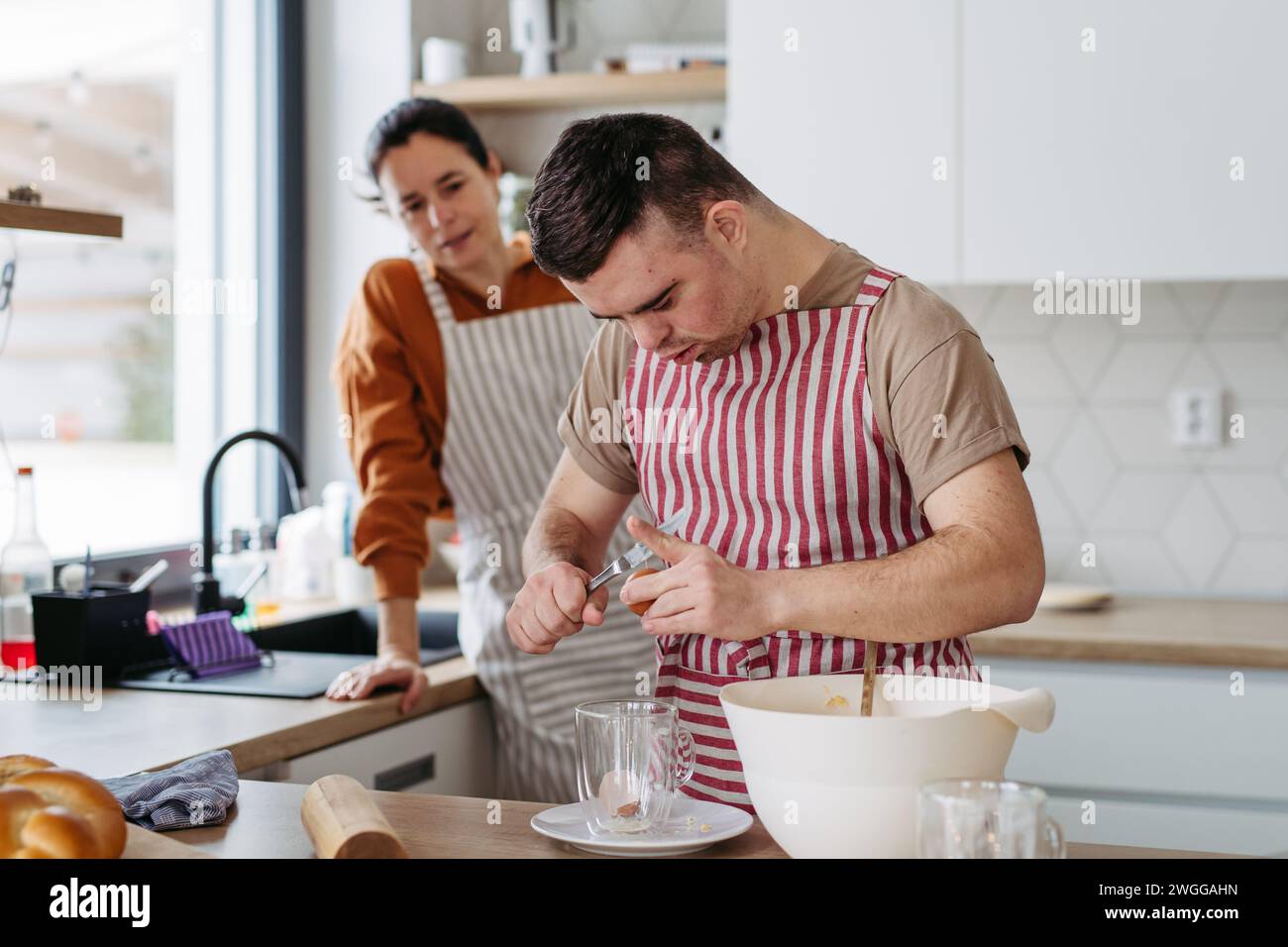 Young man with Down syndrome preparing breakfast with his mother at ...