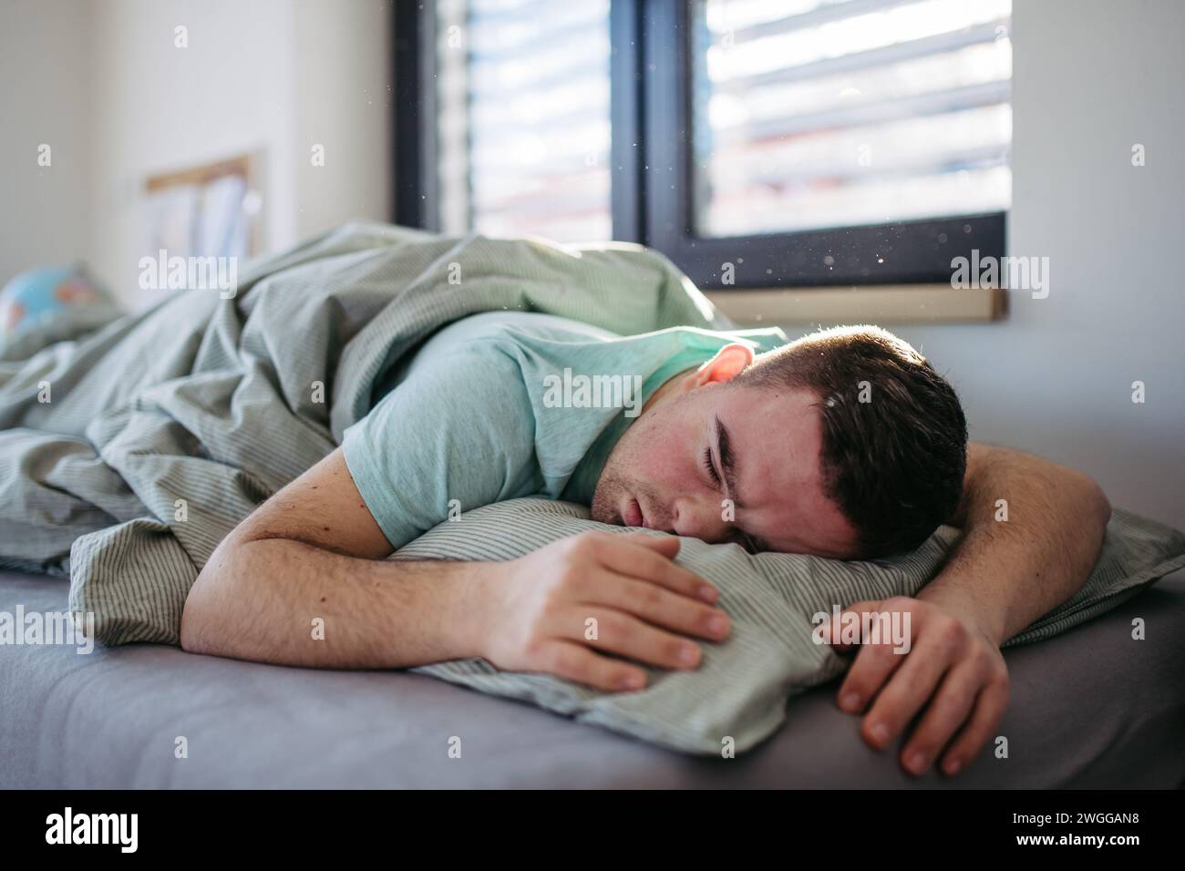 Young man with down syndrome sleeping in his bed. Lying on abdomen ...