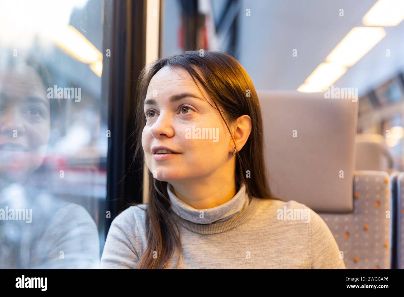 Female traveler looking with interest at scenery outside train window ...