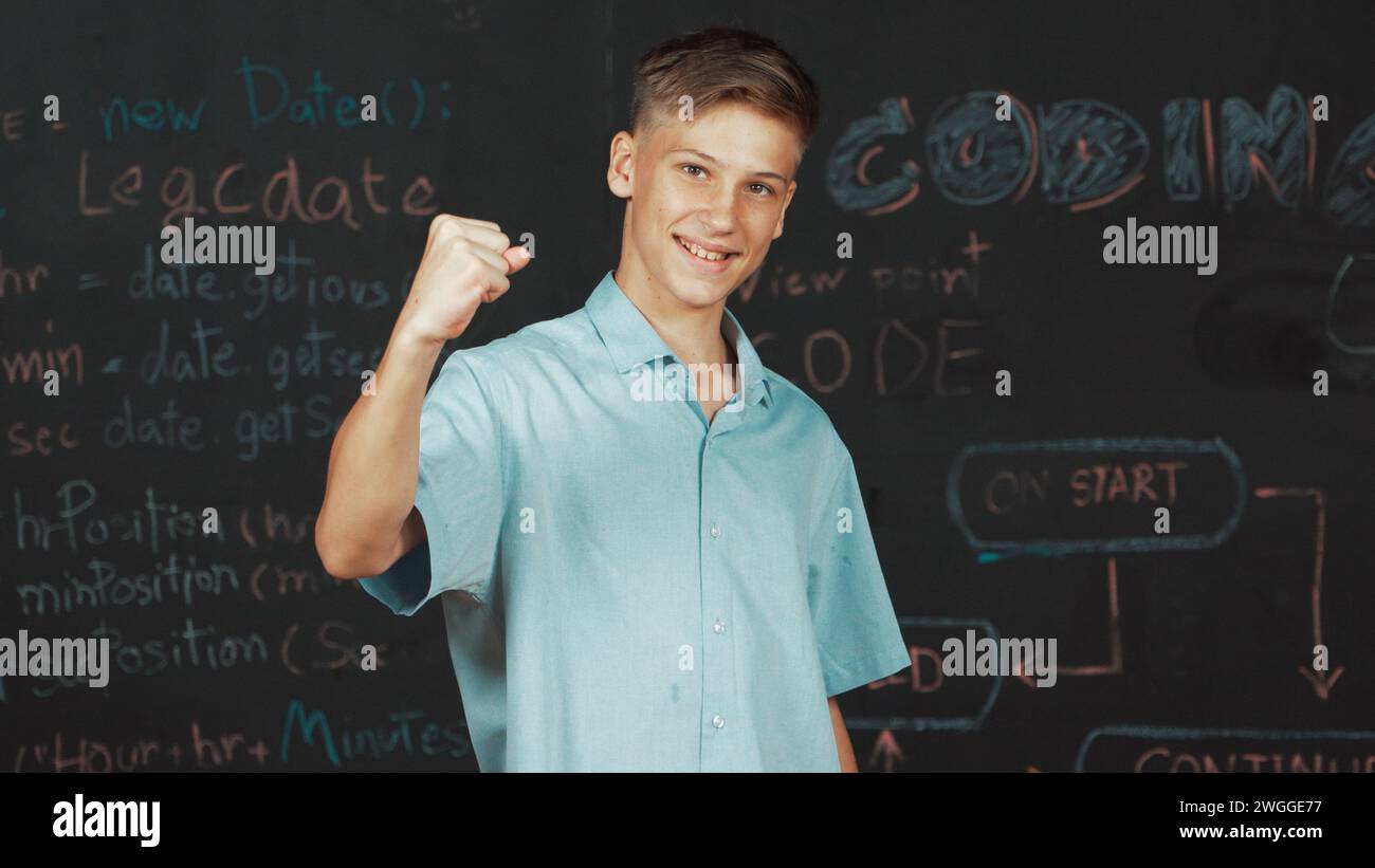 Handsome adult standing at blackboard with engineering code or prompt ...