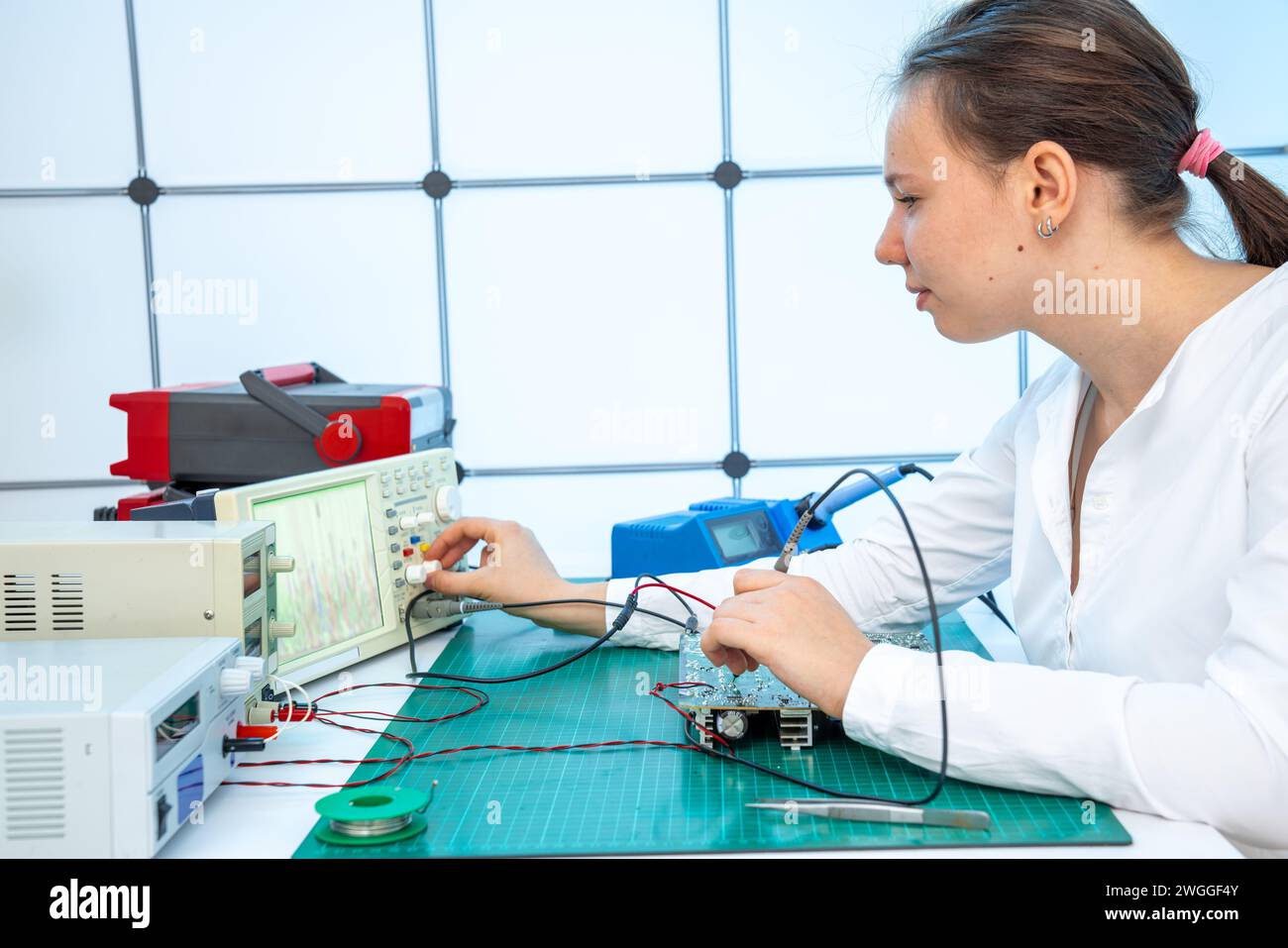 young female student doing experiments with an electronic device in a ...