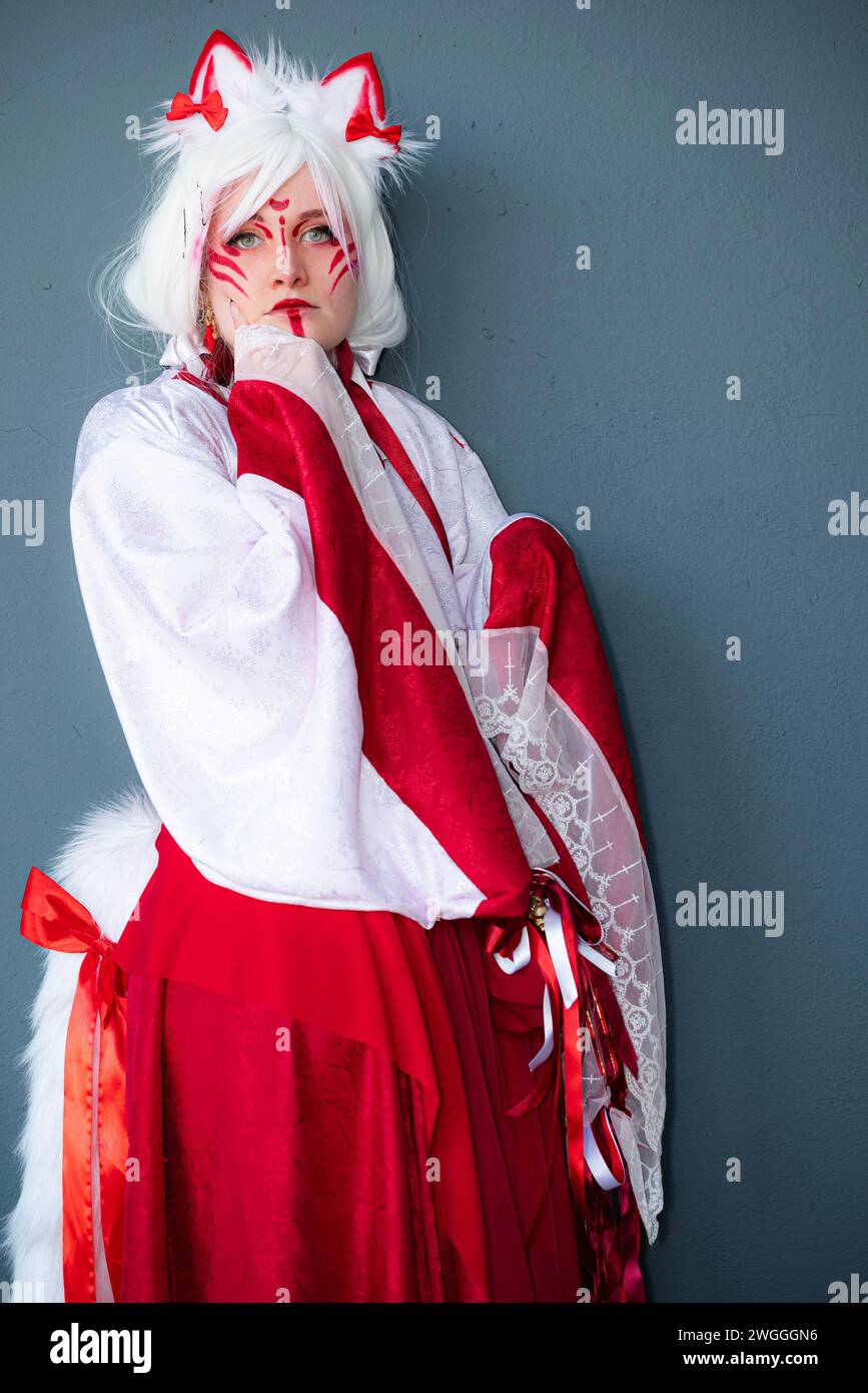 A cosplayer dressed in a Japanese white and red cat priestess costume ...