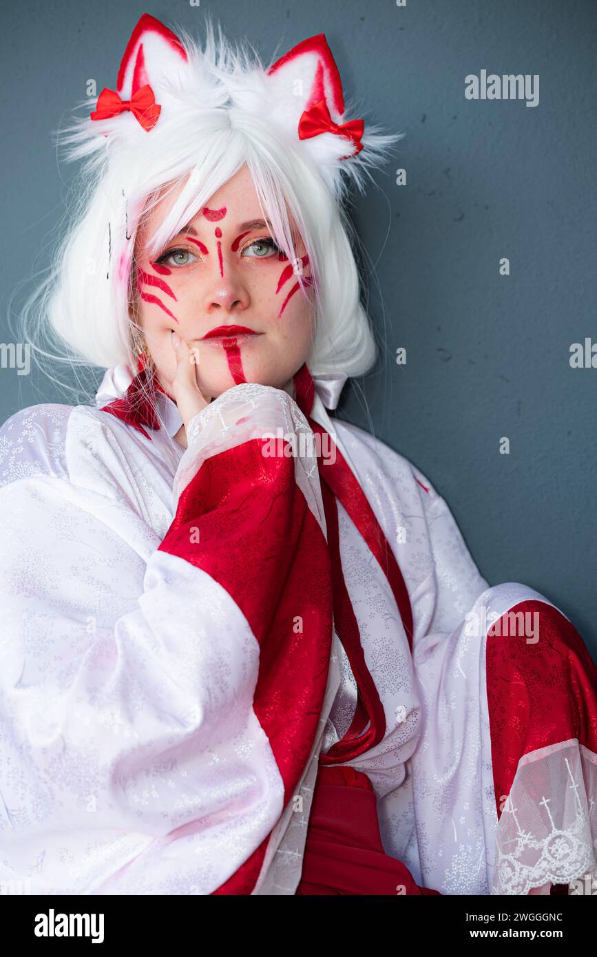 A cosplayer dressed in a Japanese white and red cat priestess costume ...