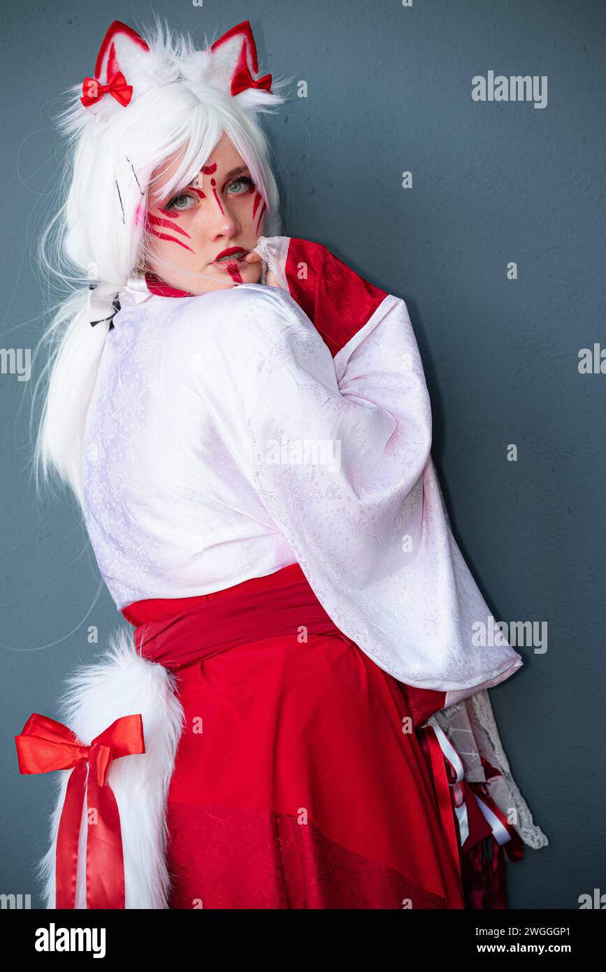 A cosplayer dressed in a Japanese white and red cat priestess costume ...