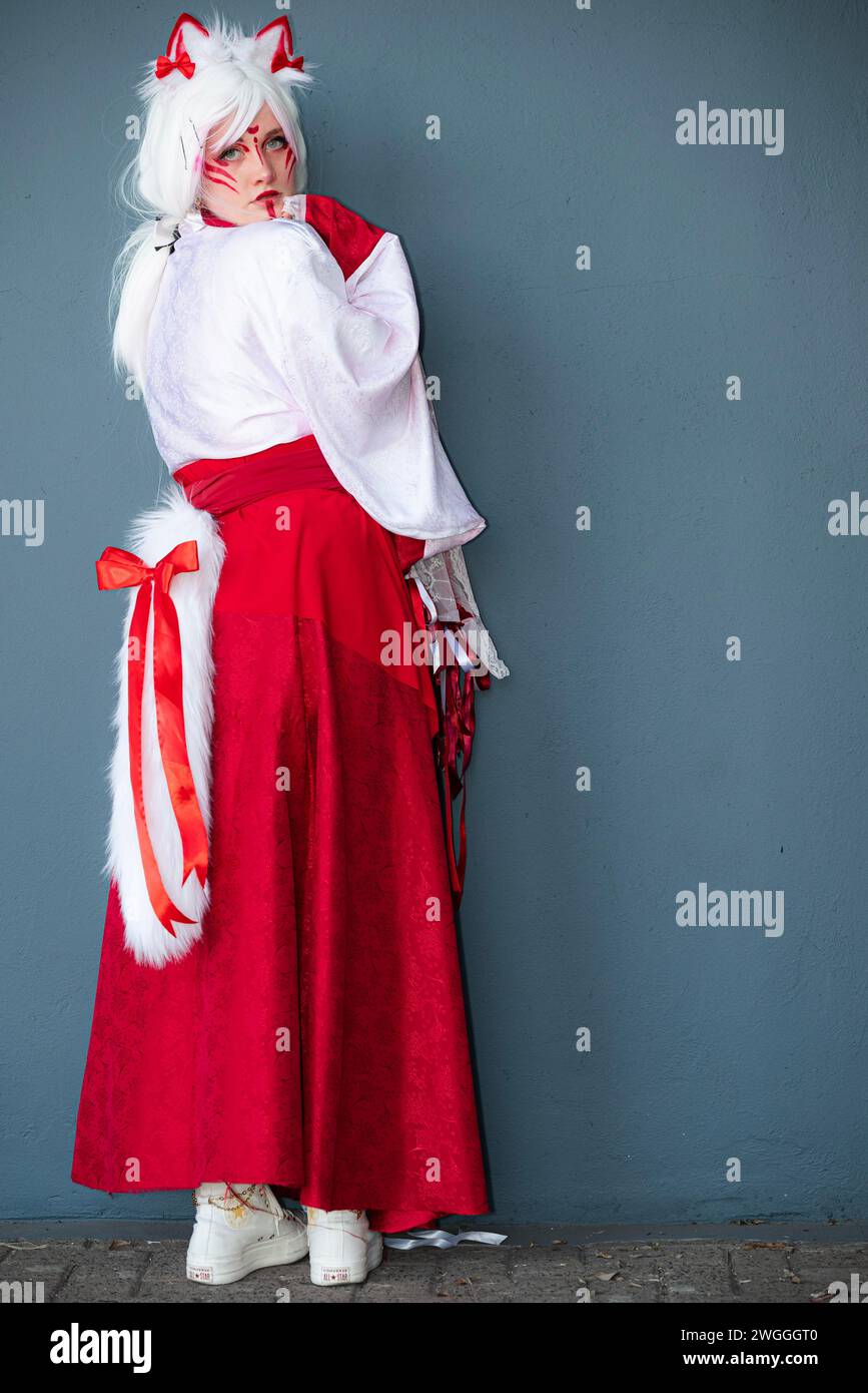 A cosplayer dressed in a Japanese white and red cat priestess costume ...