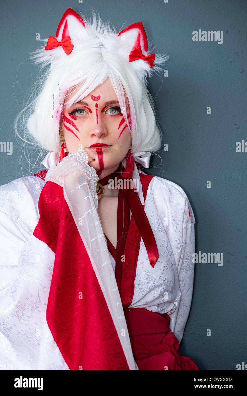 A cosplayer dressed in a Japanese white and red cat priestess costume ...