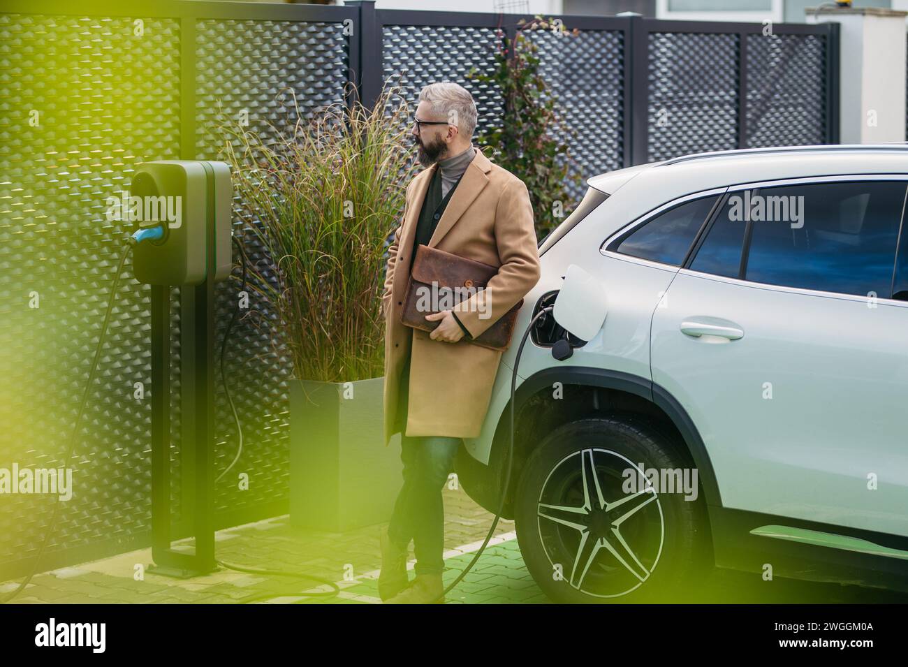 Businessman charging electric car before going to office. An electric ...