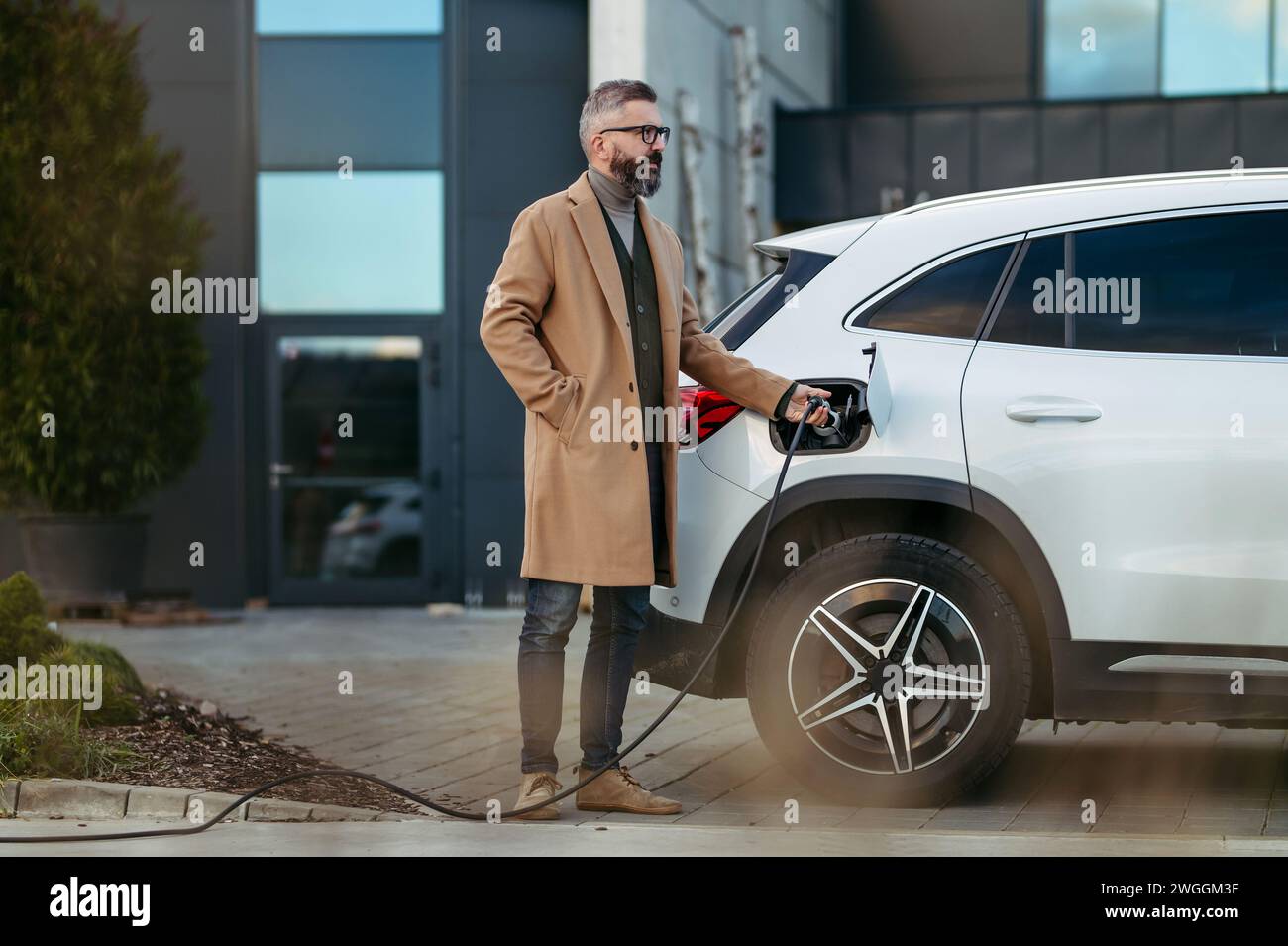 Businessman charging electric car before going to office. An electric ...